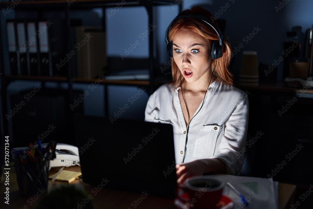 Young caucasian woman working at the office at night afraid and shocked ...