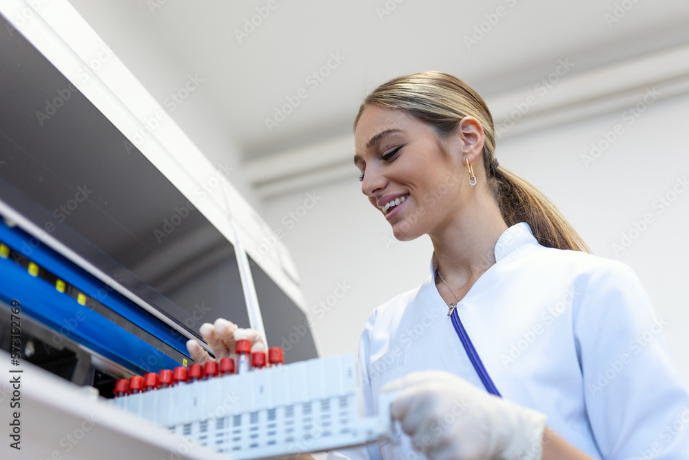 Portrait of a young female laboratory assistant making analysis with ...