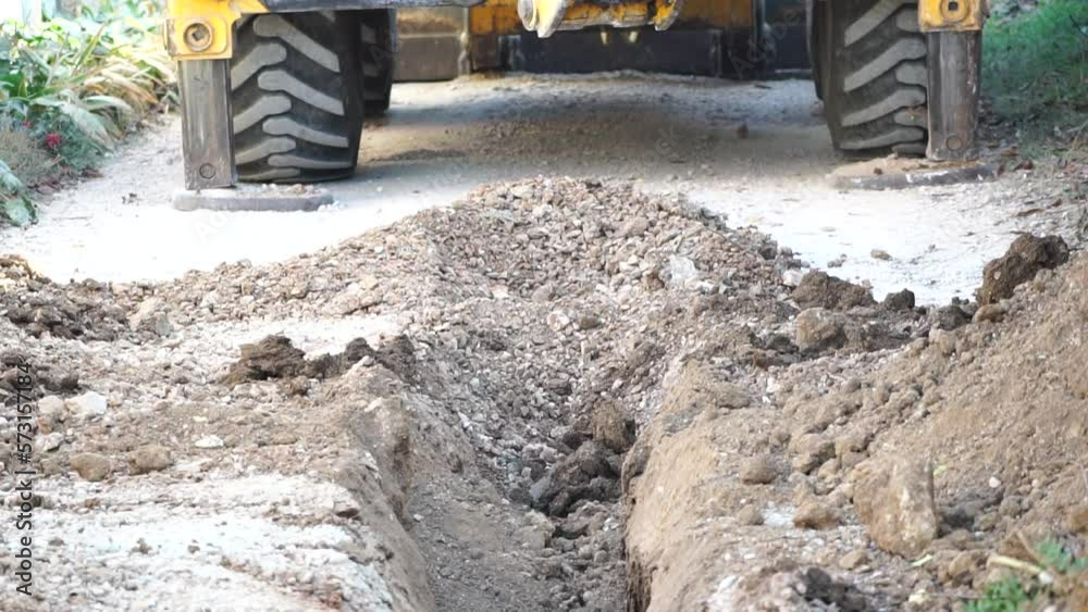 Excavator digs a trench to lay pipes. Close up of an excavator digging ...