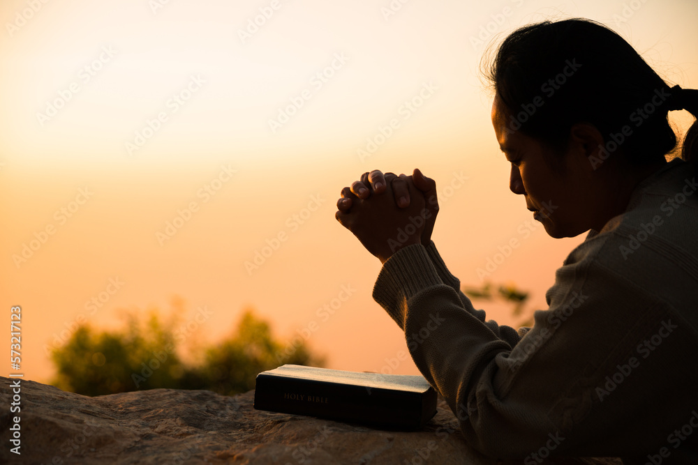 Silhouette of woman kneeling down praying for worship God at sky ...