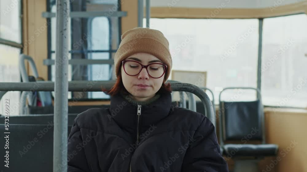 Spectacled girl in winter clothes rides in public transport, thinks ...