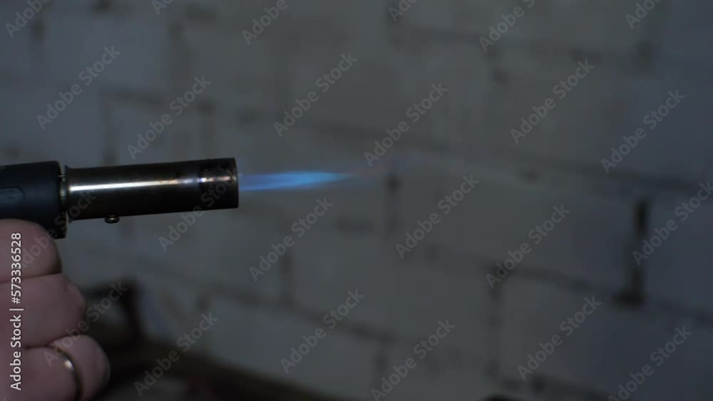A man holding a blowtorch in his hands lights up. The blowtorch bursts ...
