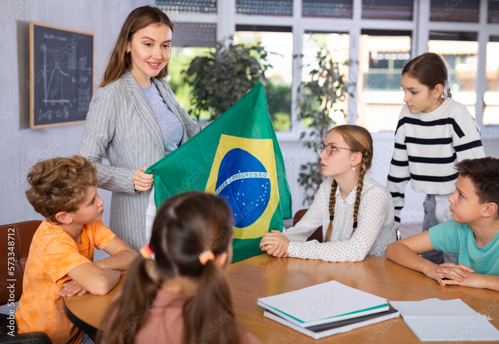 Foto de Positive young female teacher holding national flag of Brazil ...