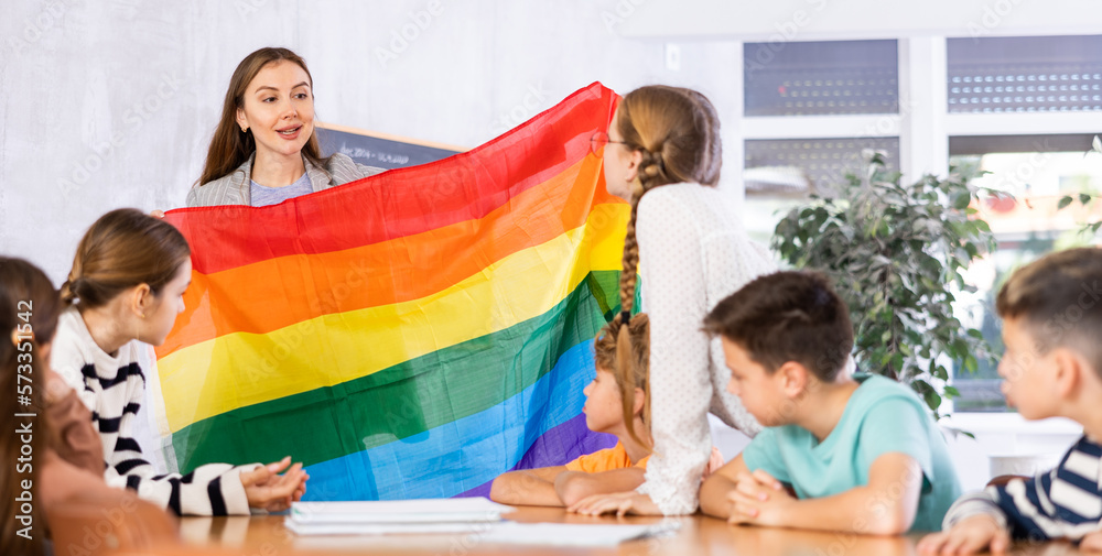 Young female teacher showing flag of LGBT to schoolchildren preteens ...