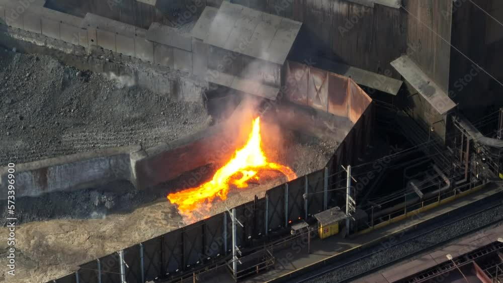 Hot molten steel spewing from USS steel mill building. Long aerial zoom ...