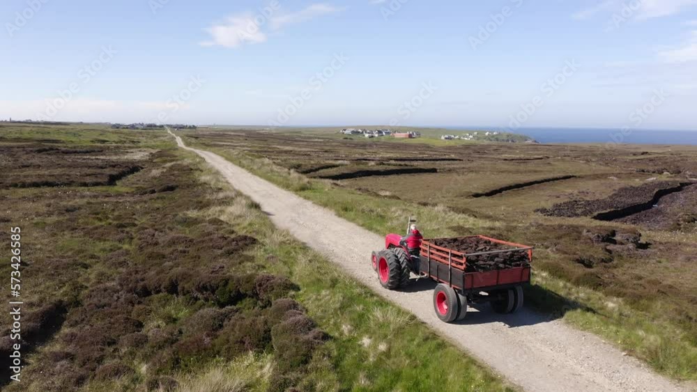 Drone shot following a tractor full of peat. The driver is taking his ...