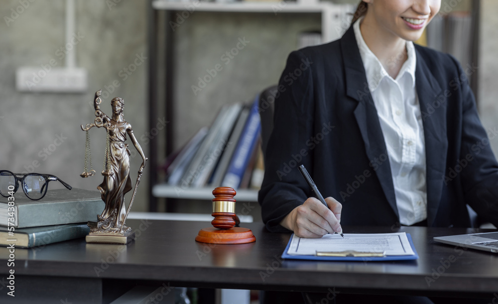 Statue of Justice and female lawyer in suit at workplace with laptop ...