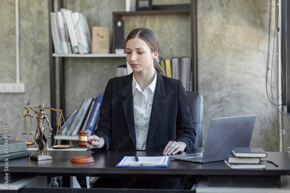 Statue of Justice and female lawyer in suit at workplace with laptop ...