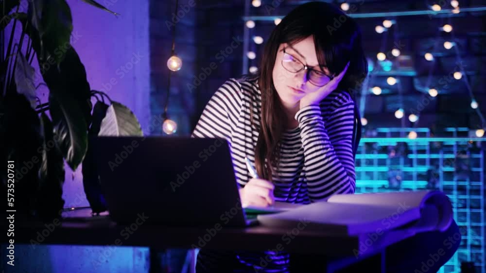 Boring tired young student with glasses studying on laptop computer and ...