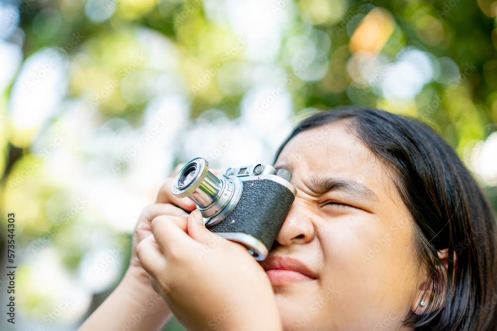film camera in the hands of a girl taking a picture. Green trees ...