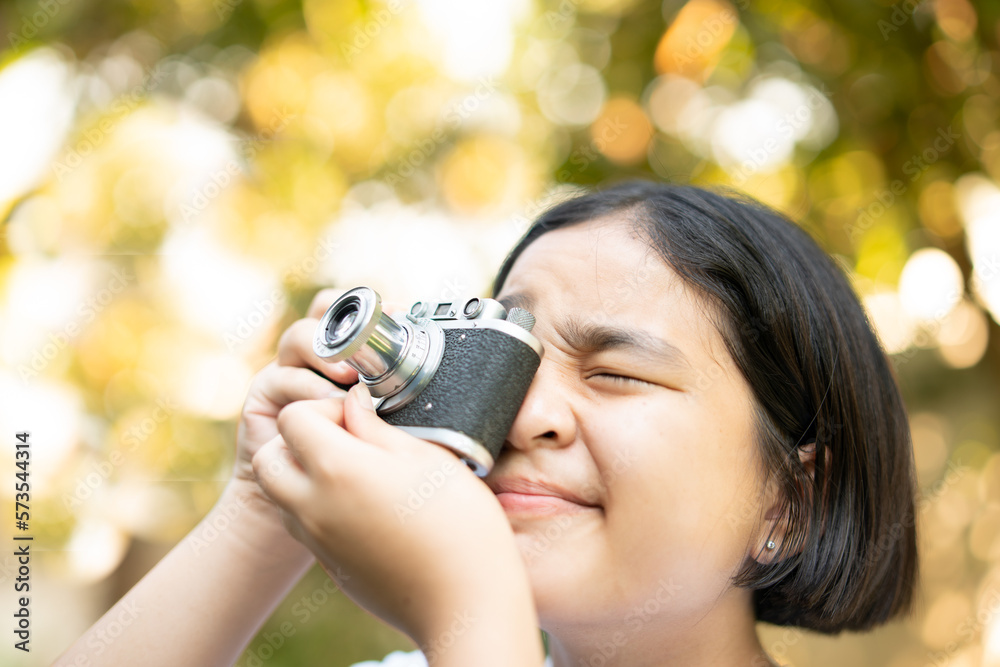 film camera in the hands of a girl taking a picture. Green trees ...