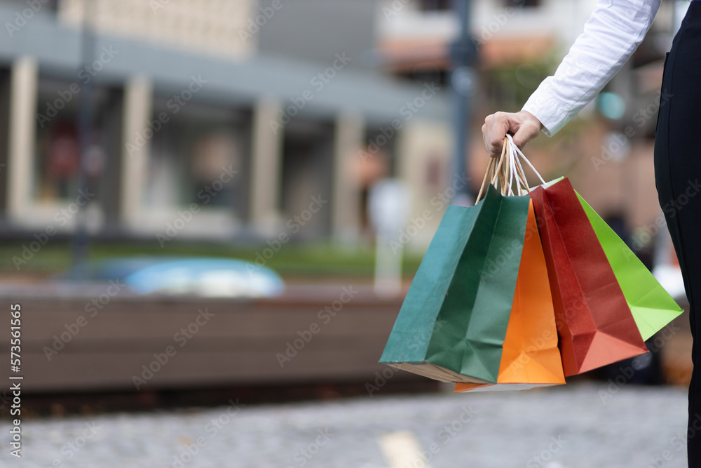 Cheerful and attractive young Asian woman carrying shopping bags ...