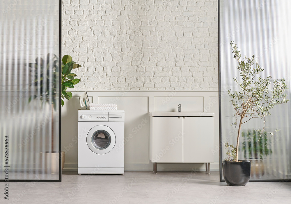 Washing machine in the bathroom, white brick wall background, vase of ...