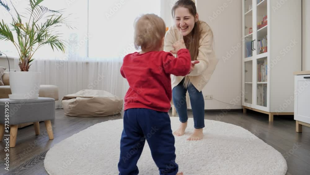 1 year old baby boy learning walking and making steps on carpet towards ...
