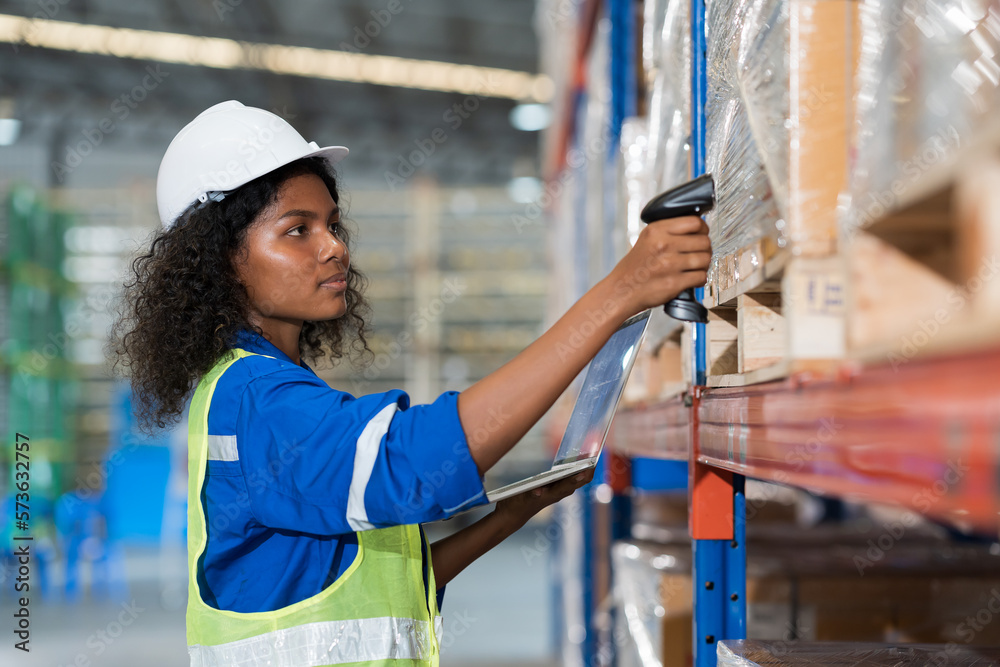 Foto de African American female warehouse worker scanning barcodes on ...