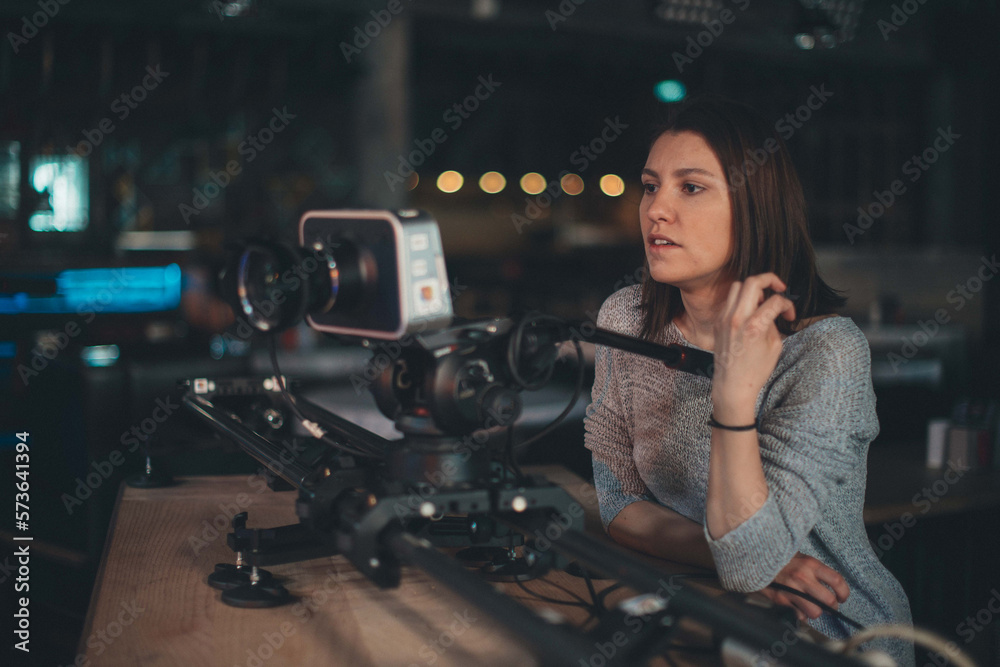 A young female director of photography at work behind a movie camera on ...
