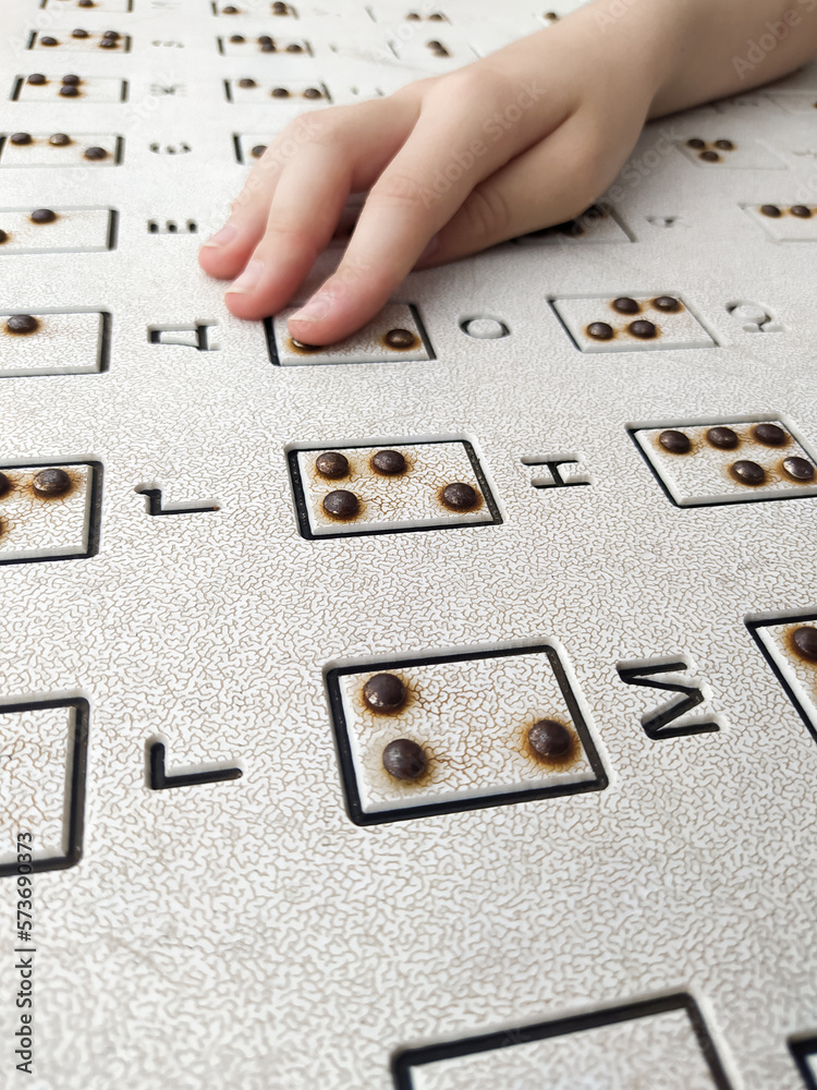 Child's hand is reading Braille outdoors close-up. Tactile reading of ...