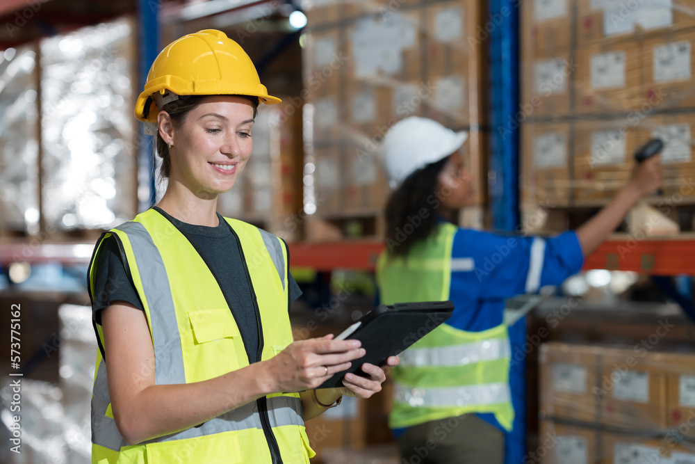 Group of female warehouse workers wearing hard hat and uniform checks ...
