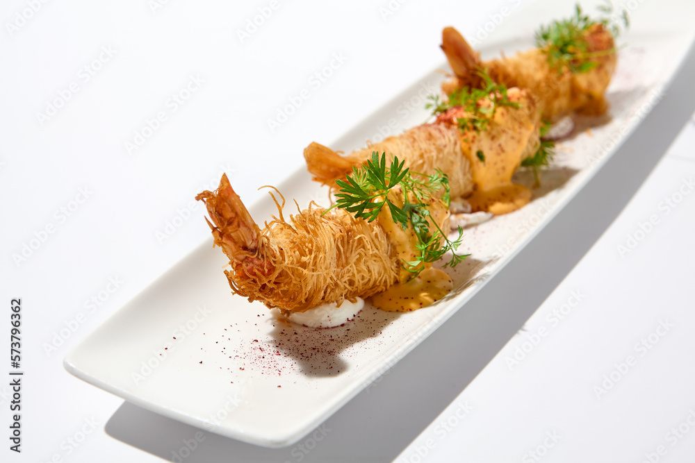 Traditional greek appetizer - kataifi wrapped shrimps on white plate ...