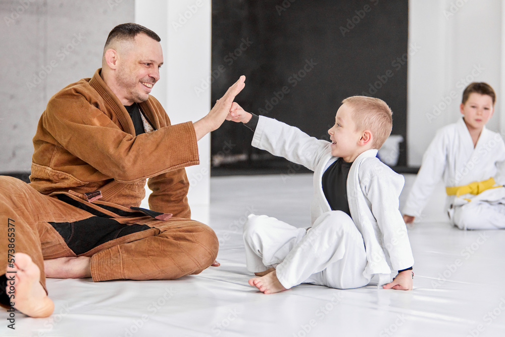 Cooperation. Friendly man, judo, jiu-jitsu coach training with little ...