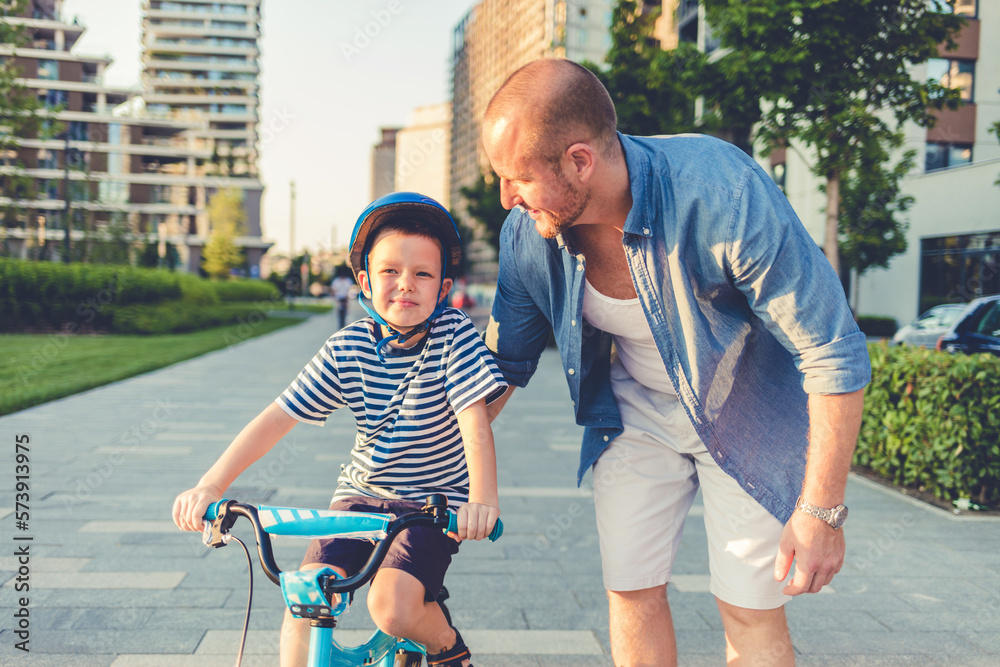 Little boy learn to ride a bicycle with help from his fahter. Front ...