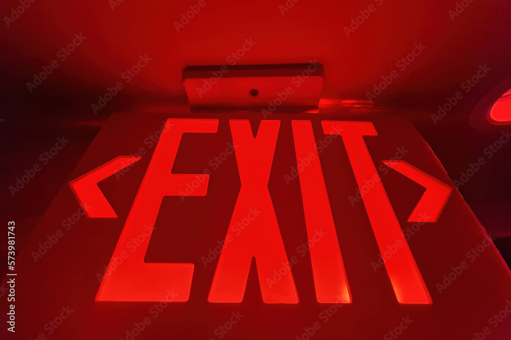 A red Exit sign. Emergency exit direction indicator on the ceiling in ...