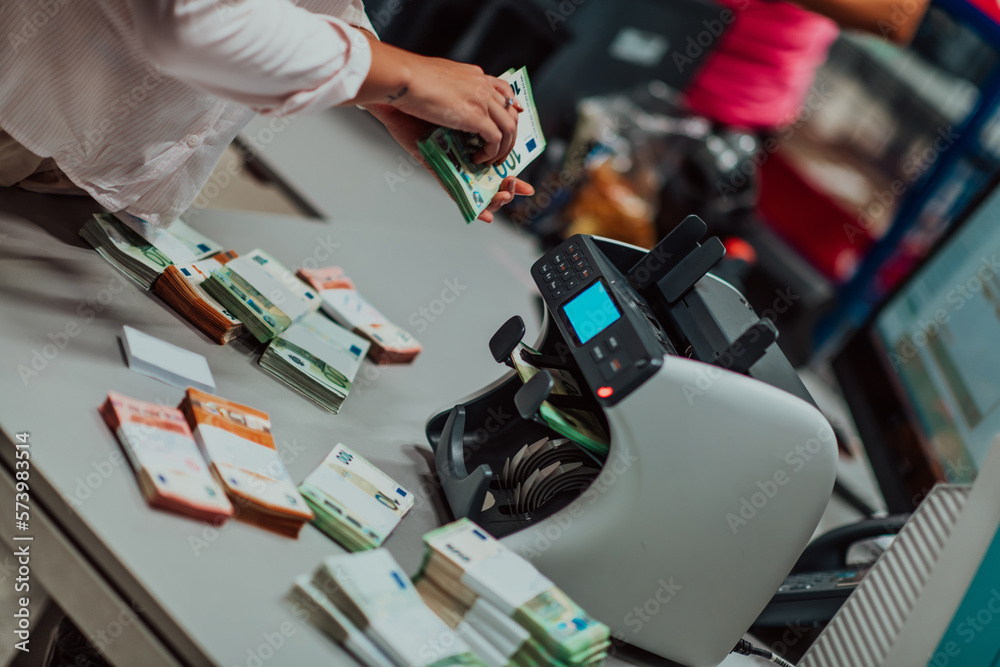 Bank employees using money counting machine while sorting and counting ...