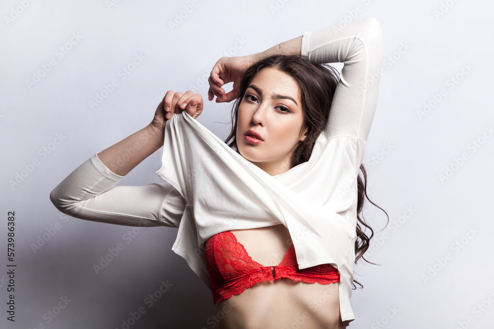 Beautiful Woman With Wavy Hair Taking Off Her Shirt Showing Her Red Underwear Expressing