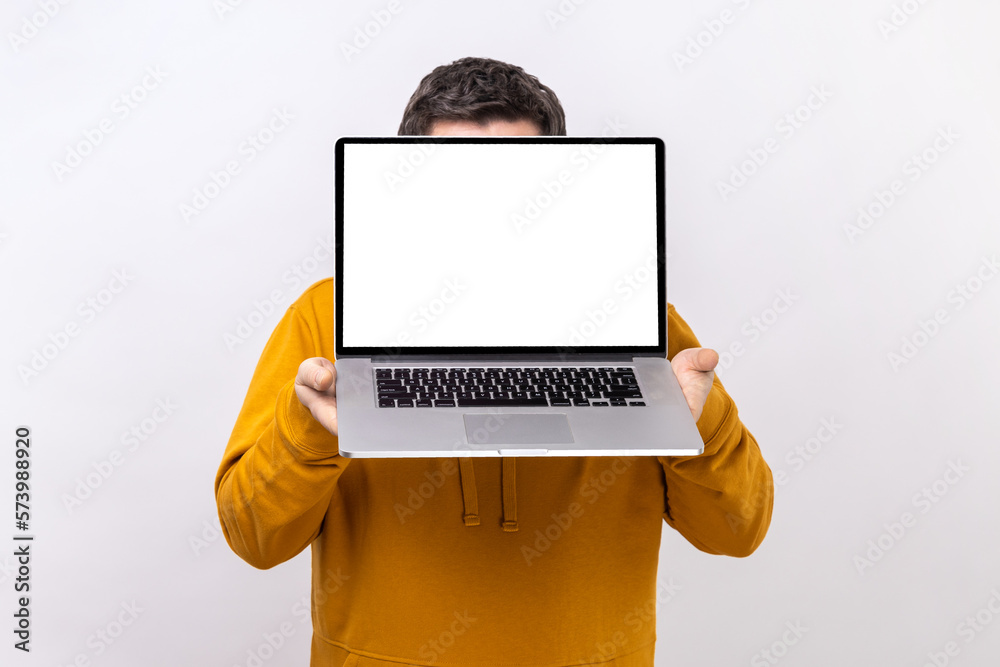 Man hiding face behind laptop with empty display and presenting new ...