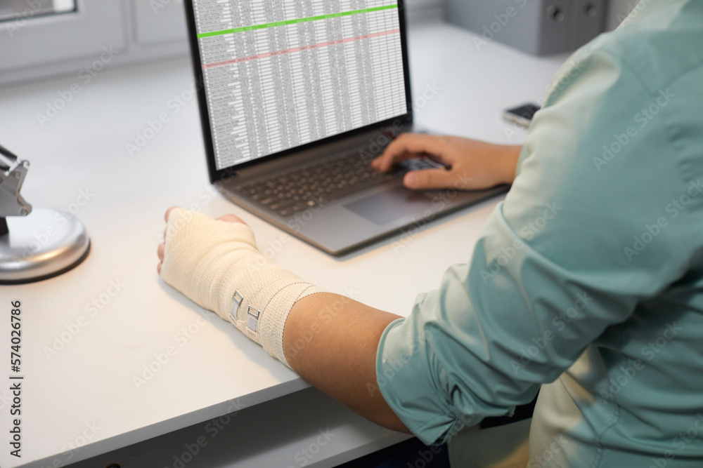 Man with a hand injury working on a laptop computer in the office. Man ...