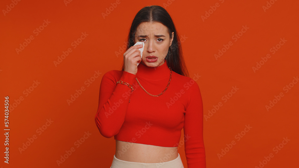 Upset disappointed pretty young woman in crop top wipes tears and cries ...