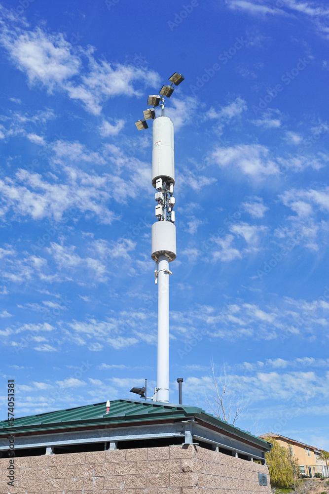 Cell phone tower and light tower next to a sports field Stock Photo ...