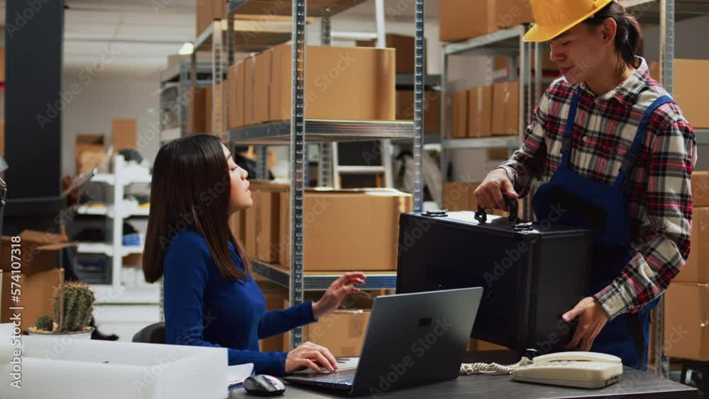 Business owner working on stock logistics with employee in storage room ...