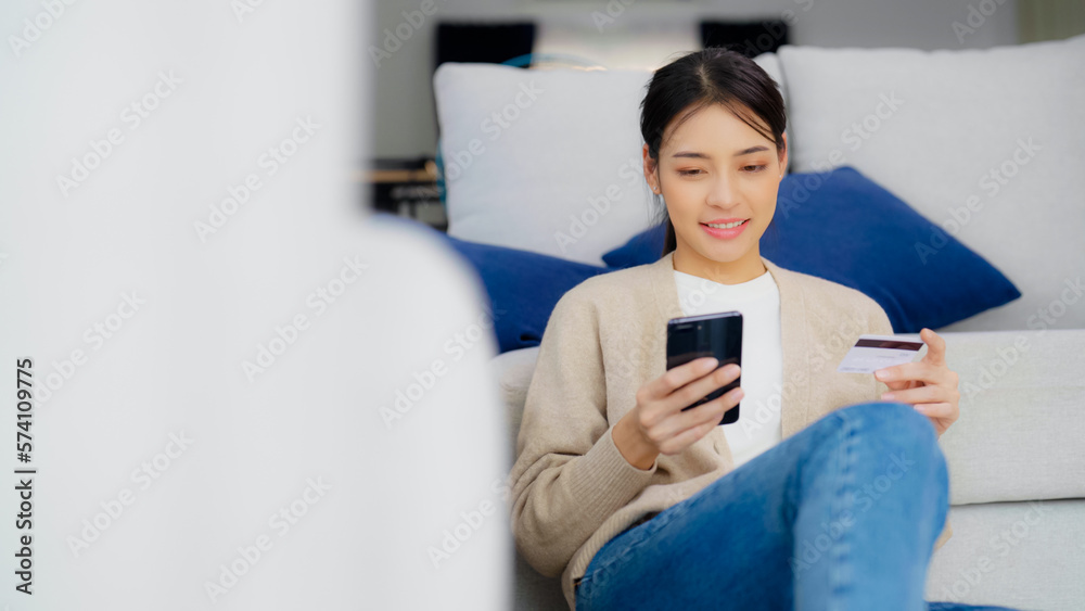 Young asian woman sitting on sofa in living room, makes online banking ...