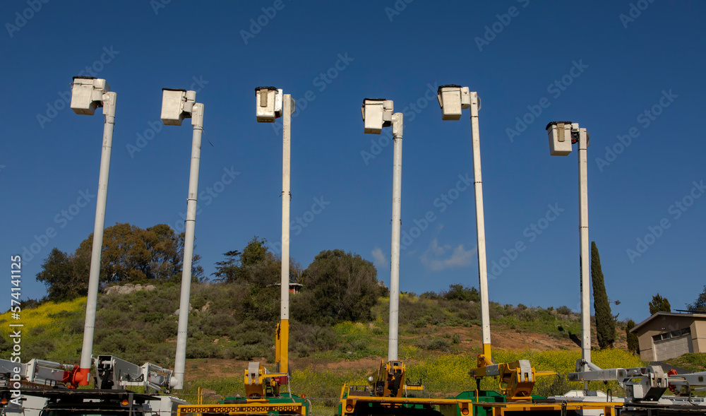 Manlift boom arms for utility work or trtee trimming against a blue sky ...