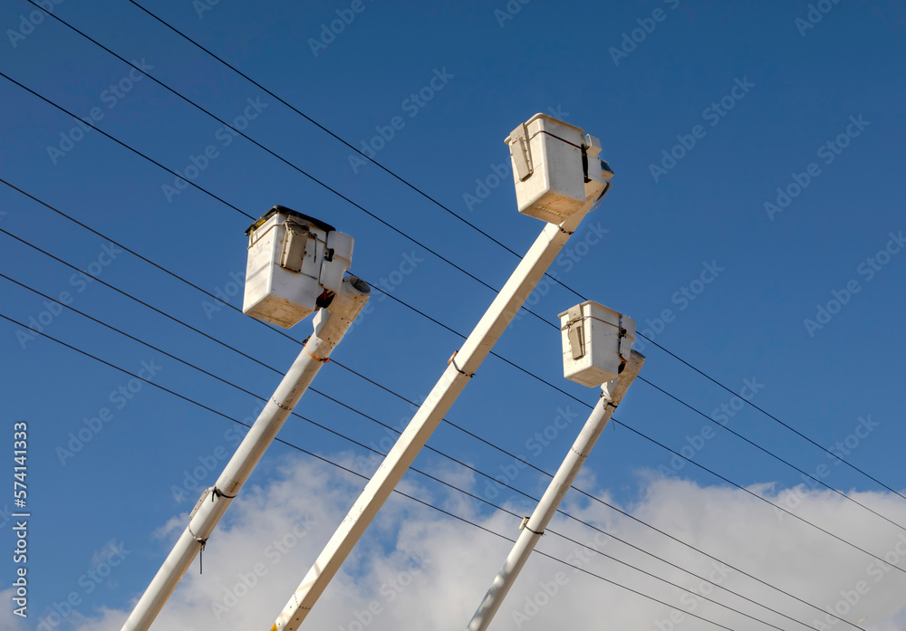 Manlift boom arms for utility work or trtee trimming against a blue sky ...