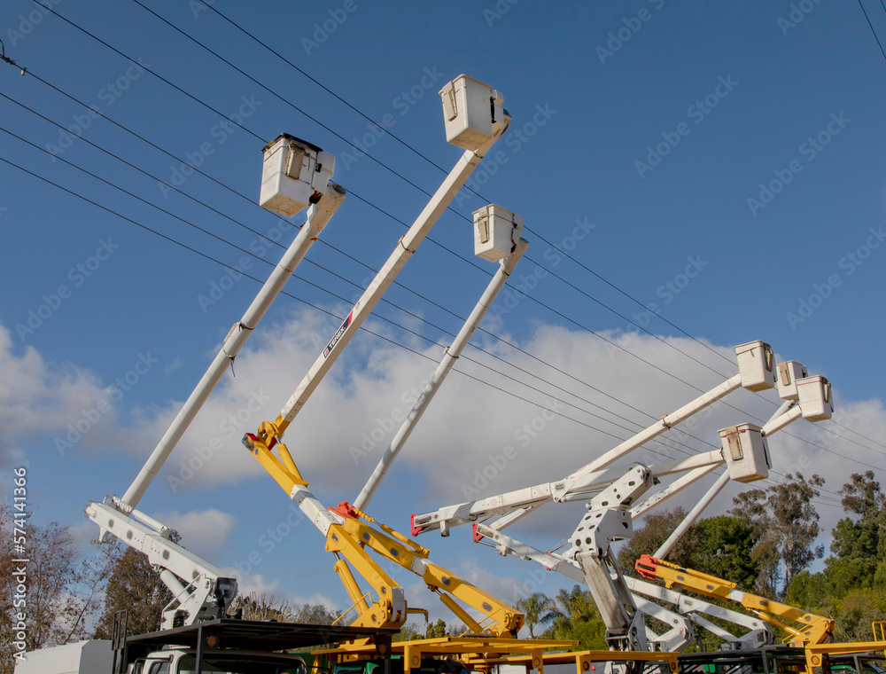 Manlift boom arms for utility work or trtee trimming against a blue sky ...