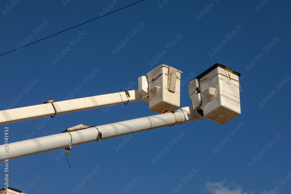 Manlift boom arms for utility work or trtee trimming against a blue sky ...