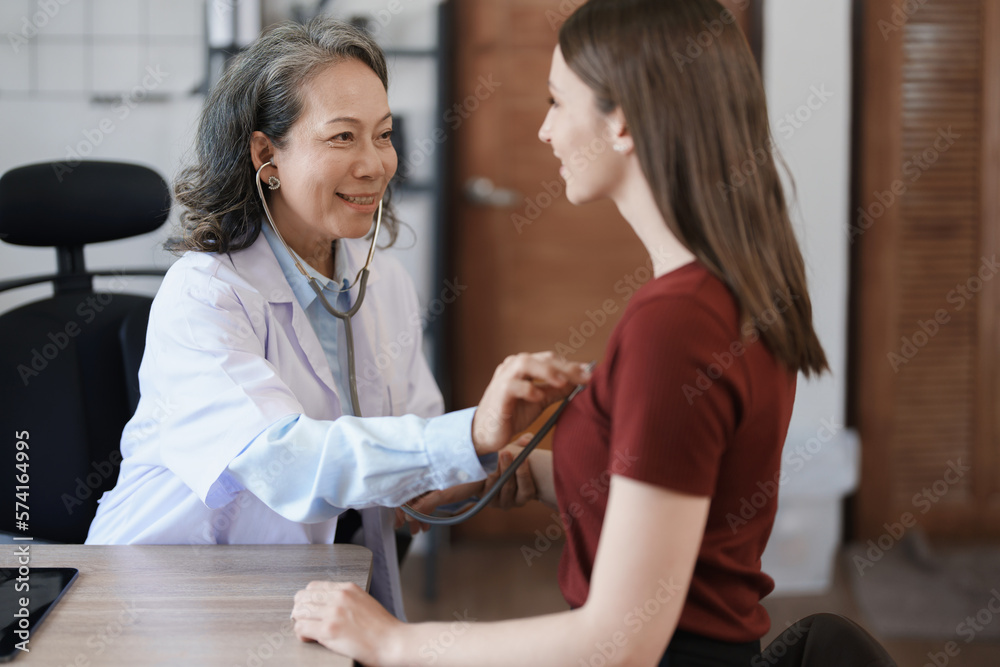 Portrait of a female doctor using a stethoscope to check the pulse of ...