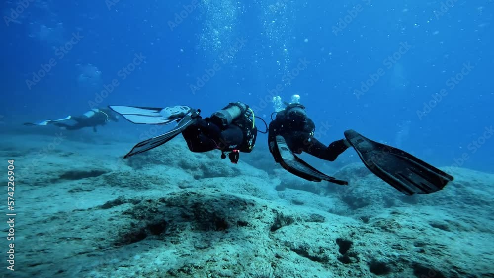 Two men scuba diving relaxed underwater follow shot; breathing and ...