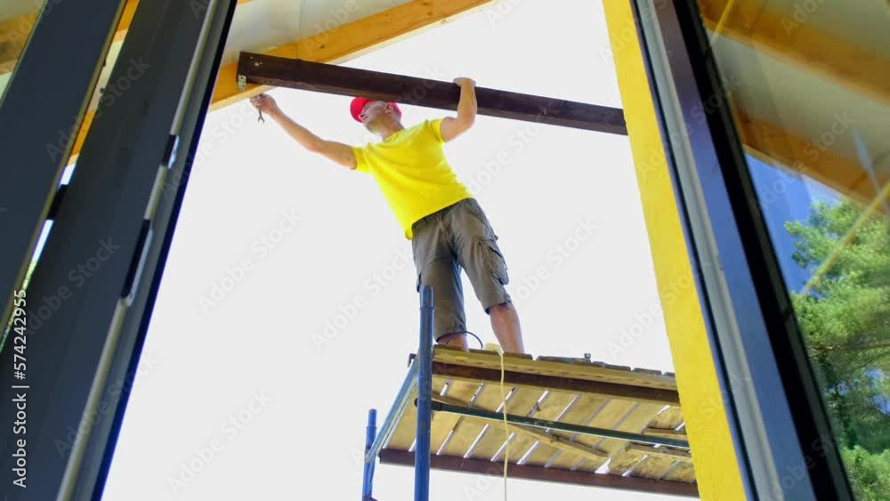 Male builder makes exterior decoration of private house in the style of ...