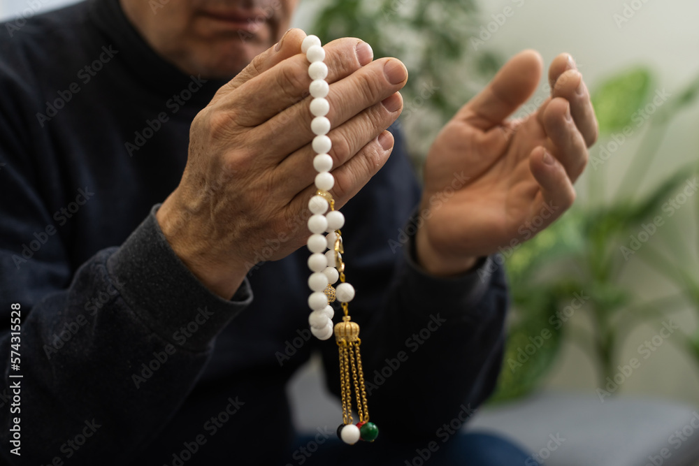 Praying hands of an old man holding rosary beads. Stock Photo | Adobe Stock