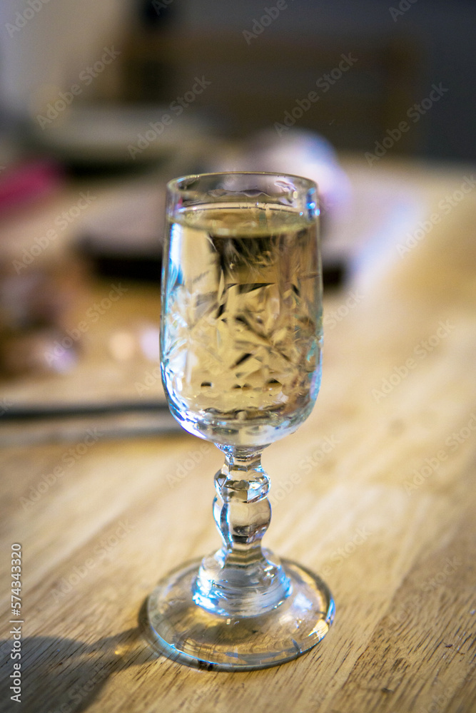 One glass filled with rakija standing on wooden table in the kitchen ...