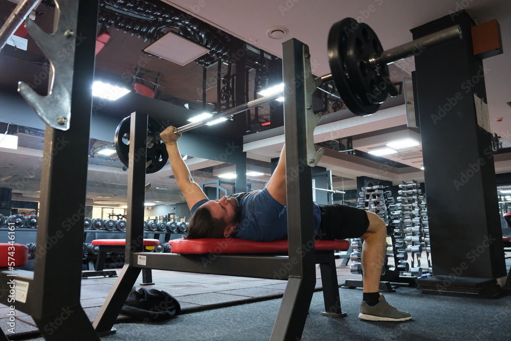 February 21, 2023 Ukraine, Dnipro. Barbell bench press. A young athlete ...