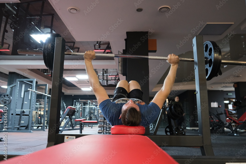 February 21, 2023 Ukraine, Dnipro. Barbell bench press. A young athlete ...