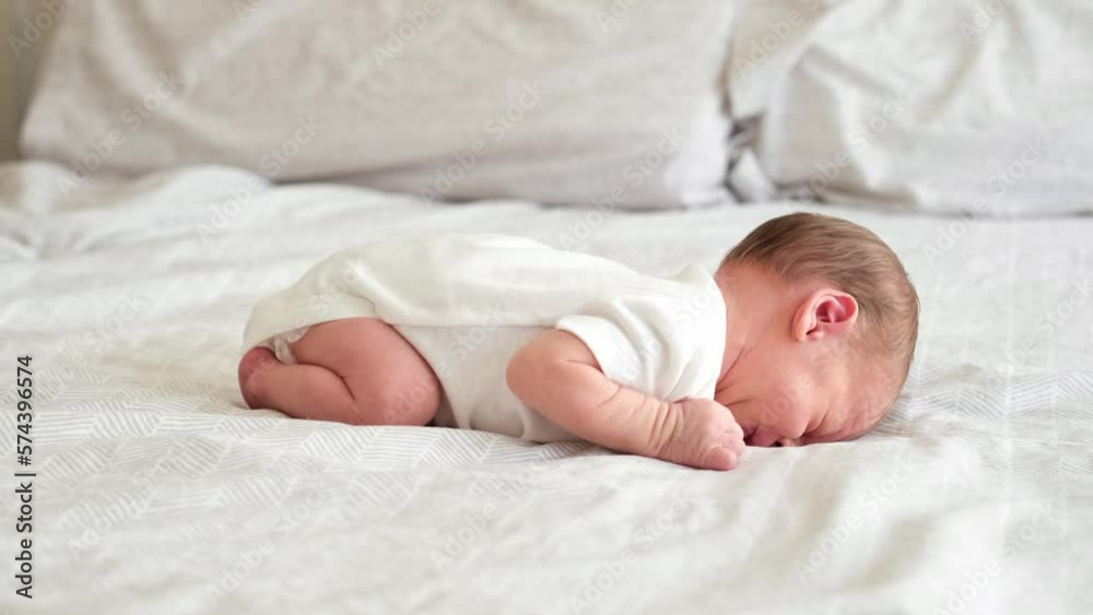 Cute adorable newborn baby boy lying on face on white bed at home while ...