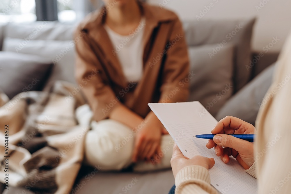 Young sad woman is sitting on the couch, holding her hands to her face ...