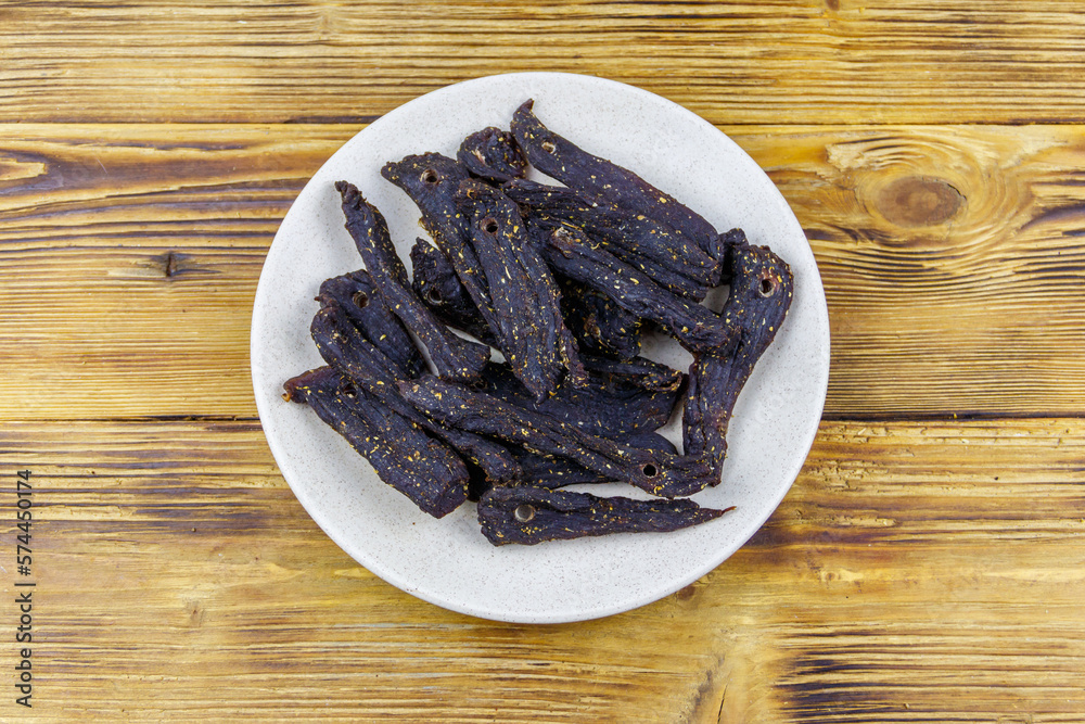 Slices of biltong (South African dried meat) on wooden table. Top view ...