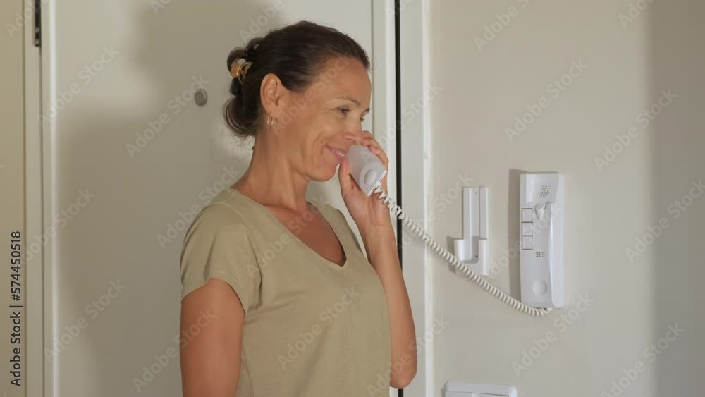 Female press intercom to open door. A curious woman takes her intercom ...