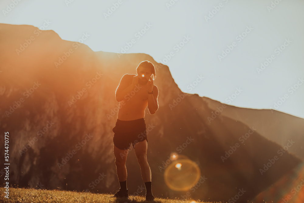 Foto de Man boxing with shadow exercising at sunset outdoor. Port ...